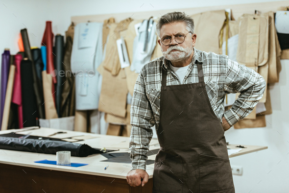 confident male craftsman in apron and eyeglasses posing at studio Stock ...