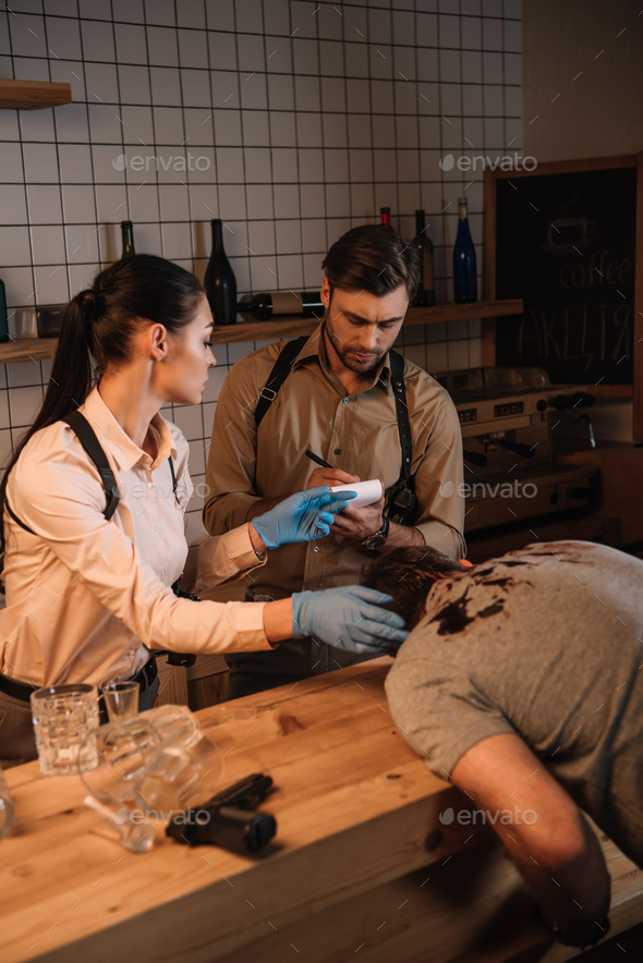 concentated female and male detectives collecting evidence from dead ...
