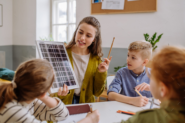Young teacher with solar panel learning pupils about solar energy ...