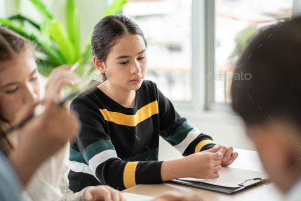 Student girl sitting at table in the classroom with classmates at ...