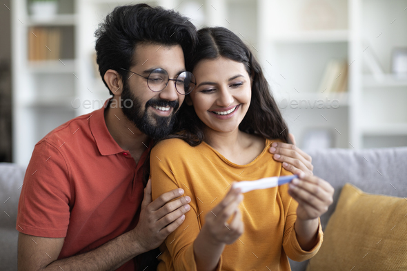 Happy Young Indian Couple Looking At Positive Pregnancy Test At Home ...