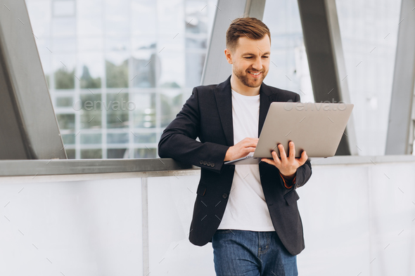 Portrait of handsome happy businessman man in suit holding laptop Stock ...