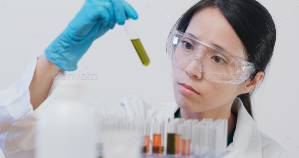 Scientist making observation on test tube Stock Photo by leungchopan
