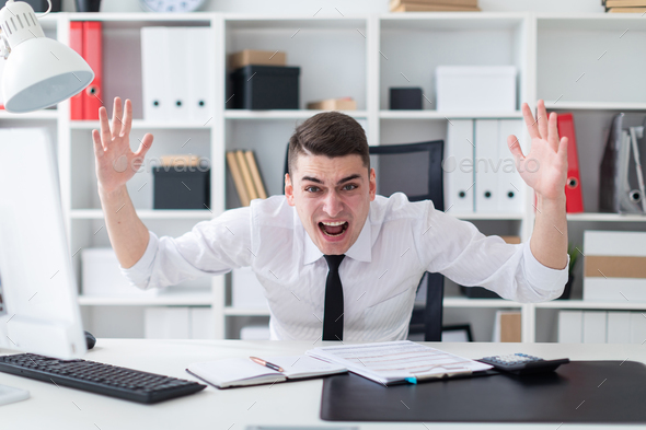 A young man sitting at a computer Desk in the office and spread his ...