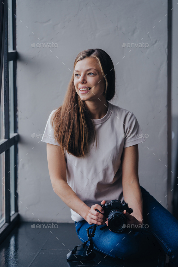 Vertical shoot of caucasian brunette woman in casual holds photo camera ...