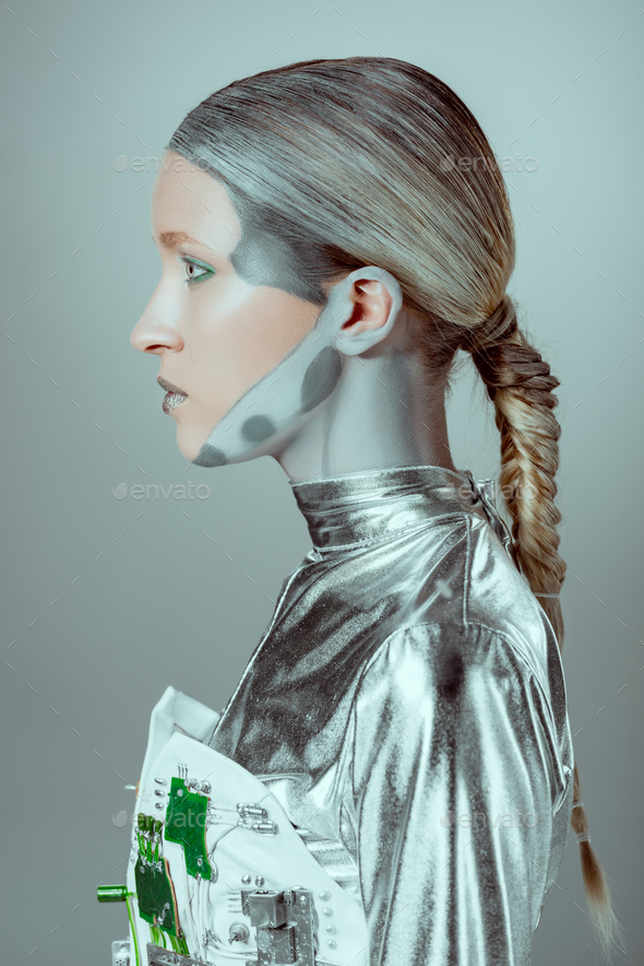 side view of futuristic silver cyborg looking away isolated on grey ...