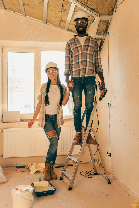 african american man in hard hat and goggles standing with power drill ...