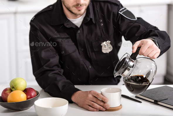 cropped view of police officer pouring filtered coffee from glass pot ...