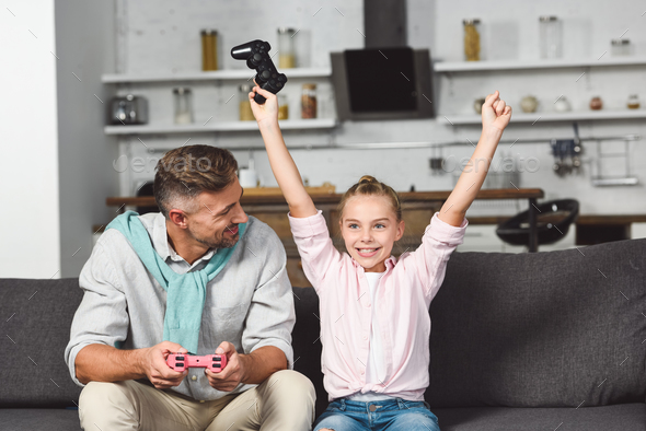 happy daughter rejoicing victory while playing video game with father ...