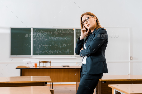 beautiful pensive female teacher in formal wear and glasses in ...