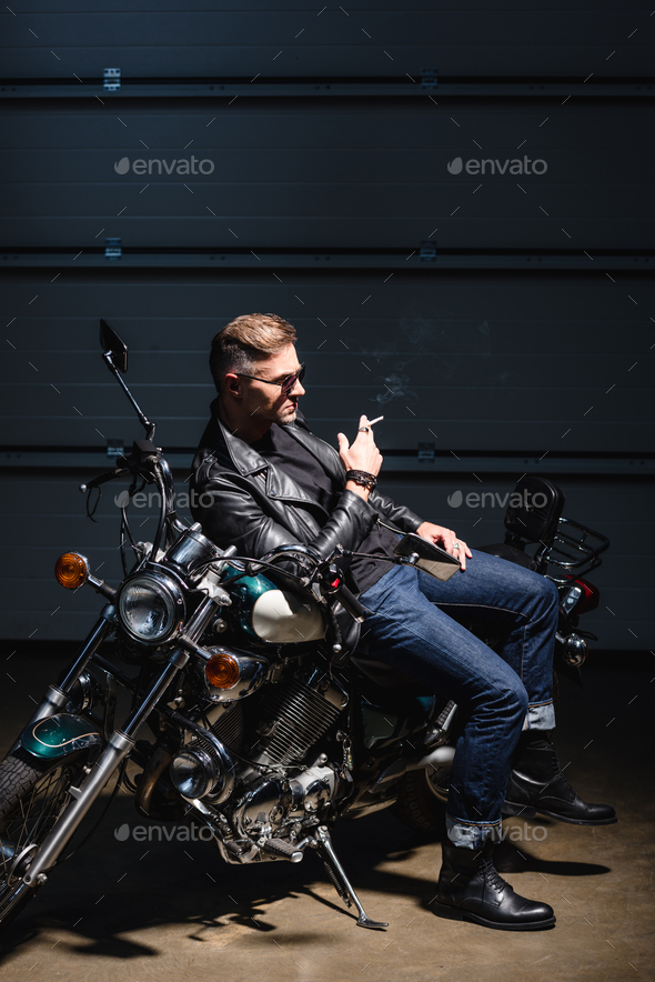 handsome guy in sunglasses leaning on motorcycle in garage Stock Photo ...