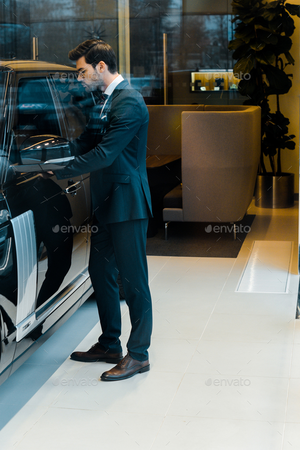 side view of businessman in suit opening door of black automobile Stock ...