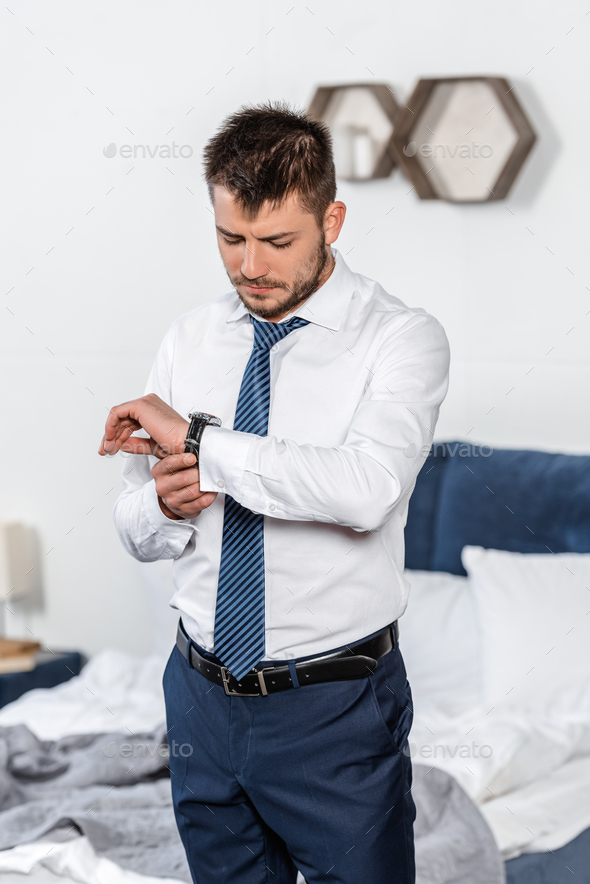 handsome man checking time at wristwatch in morning in bedroom Stock ...
