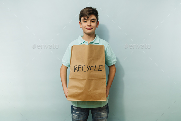 Young boy recycling with paper bag in studio. Stock Photo by karrastock