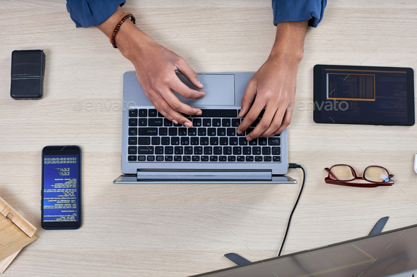 Male hands typing and writing code for mobile devices at workplace ...