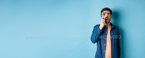 Impressed man look in awe through magnifying glass, drop jaw and stare ...