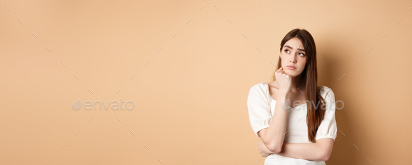 Sad young woman looking pensive at upper left corner, feeling upset or ...