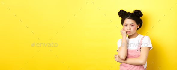 Bored asian teen girl with stylish makeup and summer clothes, looking ...