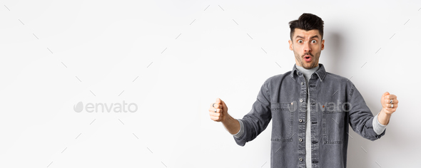 Confused man holding big size object and looking shocked, shaping large ...