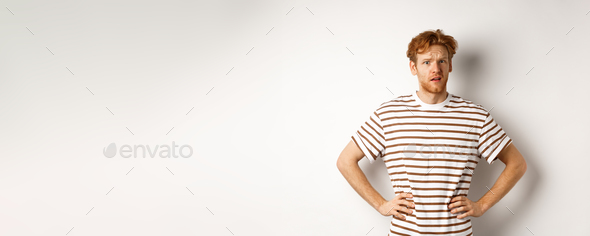 Confused and offended man with ginger curly hair staring at camera ...