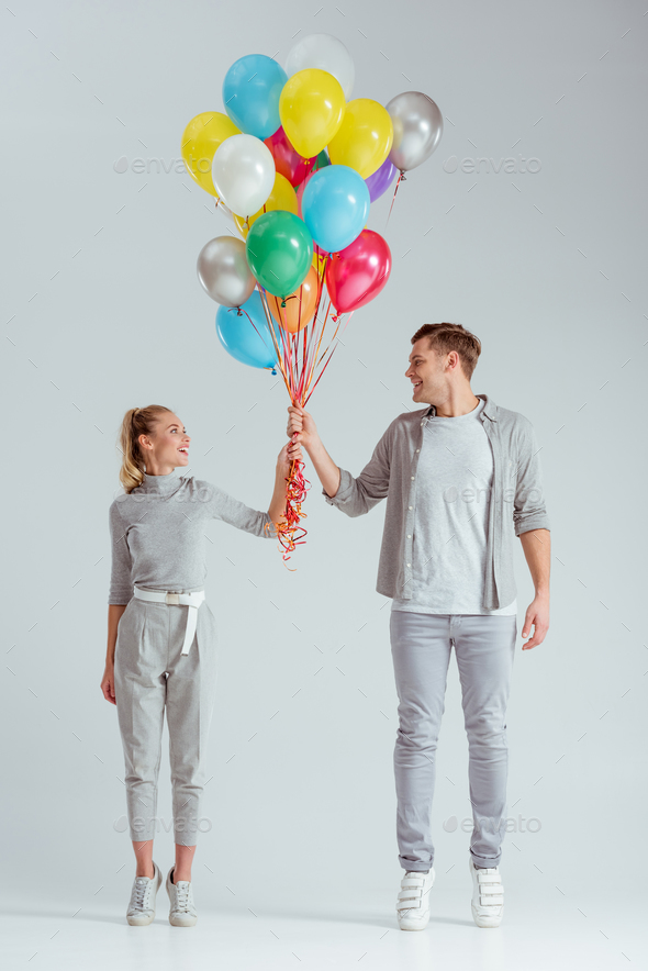 couple standing on tiptoe, looking at each other and holding bundle of ...