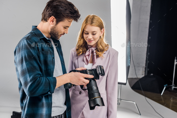handsome young photographer and smiling female model using photo camera ...