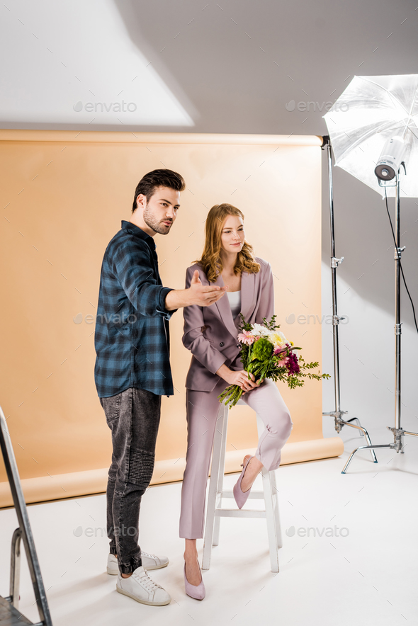 young photographer talking with beautiful female model in photo studio ...