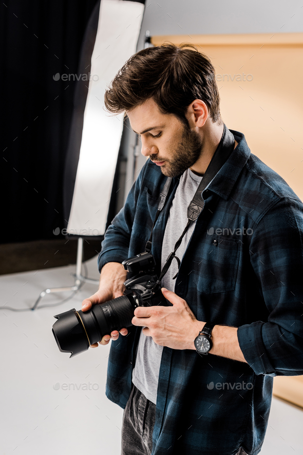 handsome young photographer using camera in photo studio Stock Photo by ...