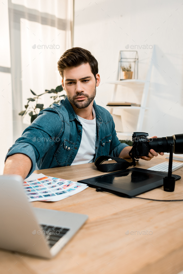 handsome young photographer using camera and laptop at workplace Stock ...