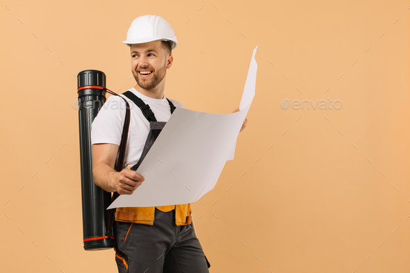Positive construction engineer examines a drawing and holds a tube on a ...