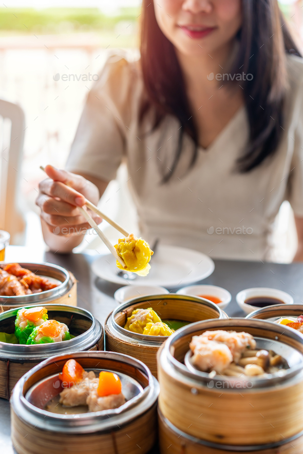 Young woman traveler eating traditional Chinese Dim Sum at restaurant ...