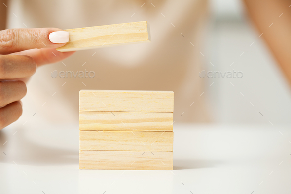 Hand picking up one wooden cube on table background. Stock Photo by ...