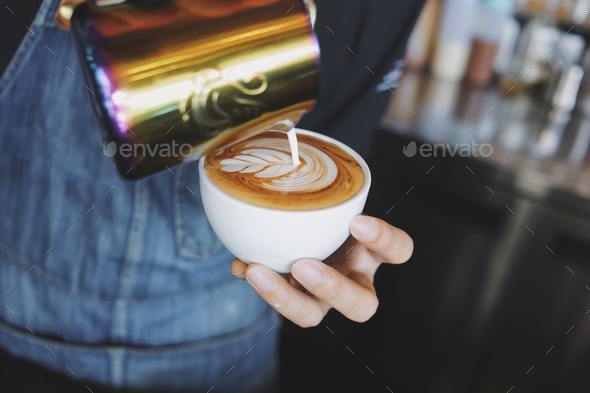 Barista making latte in coffee bar. Stock Photo by wiriyathitiporn