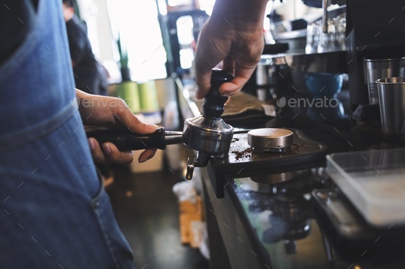 Barista making latte in coffee bar. Stock Photo by wiriyathitiporn