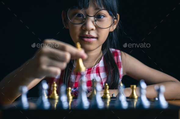 Young girl playing chess board between golden team and silver team ,she ...