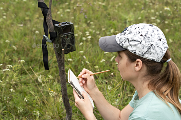 woman ecologist writing down data from trap camera to notepad ...