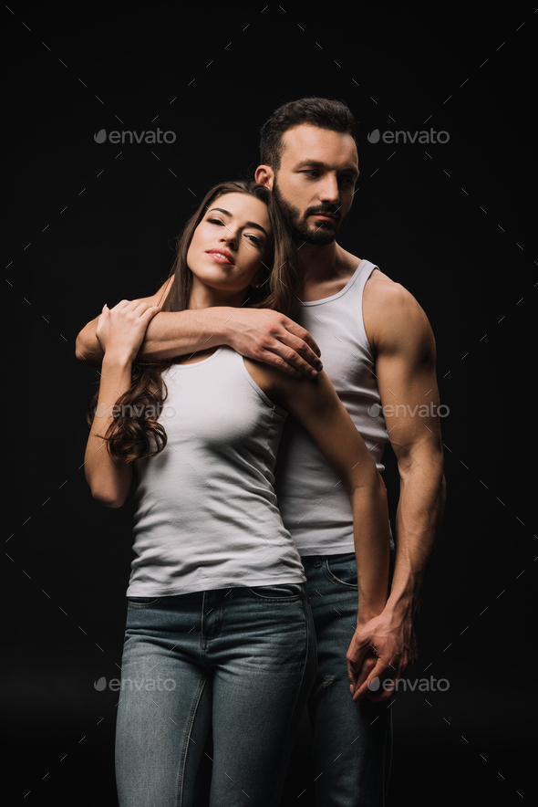 sexual man hugging attractive woman in white singlet isolated on black ...