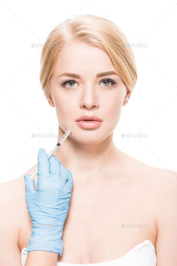 beautiful young woman receiving beauty injection in face and looking at ...