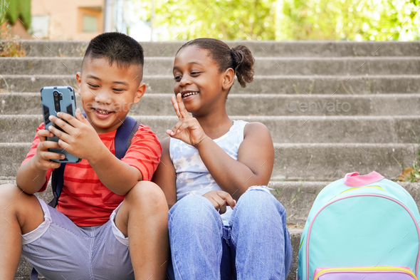 Happy multiethnic children using mobile phone for vlogging. Stock Photo ...