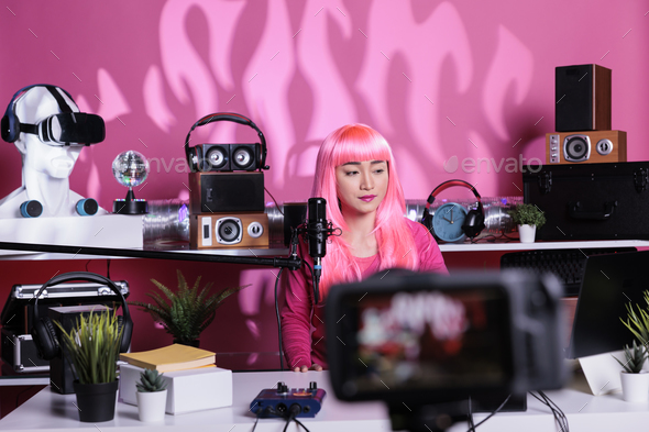 Smiling asian vlogger with pink hair talking with subscribers while ...