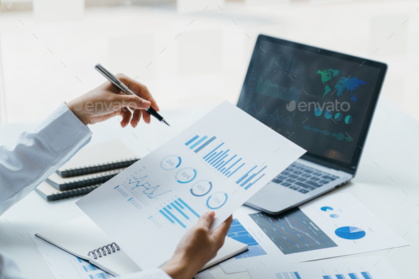 Serious focused businesswoman typing on laptop holding papers preparing ...