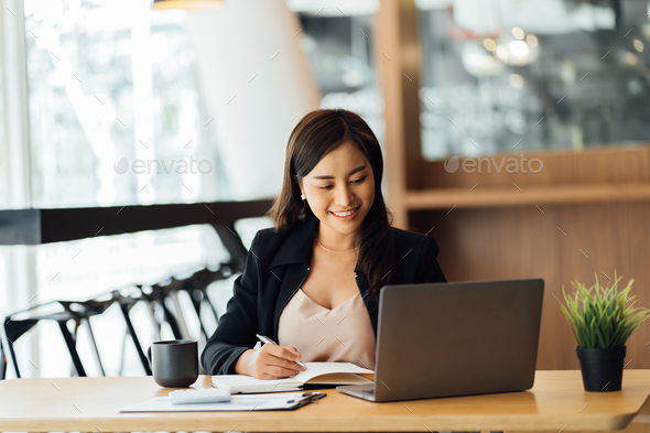 Portrait of smiling beautiful business asian woman with working in modern office desk using ...