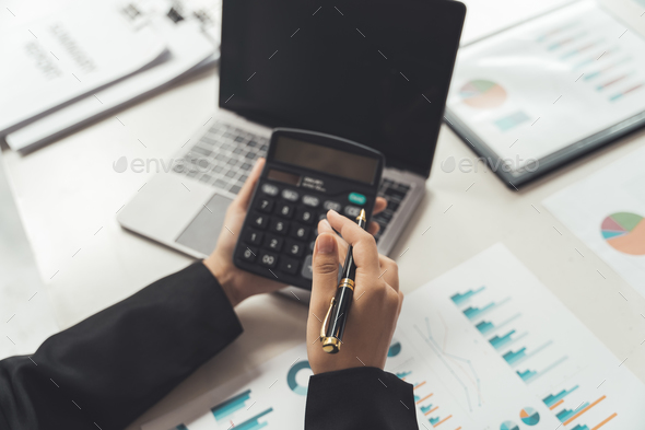 Businesswoman using calculator and laptop computer for analysis ...