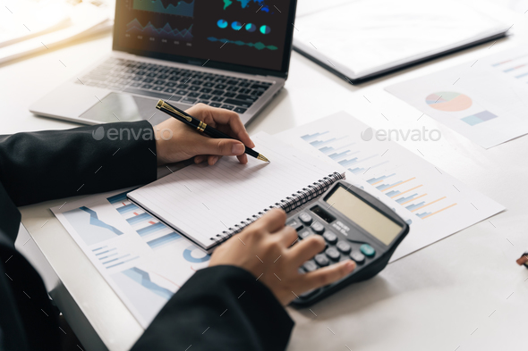 Businesswoman using calculator and laptop computer for analysis ...