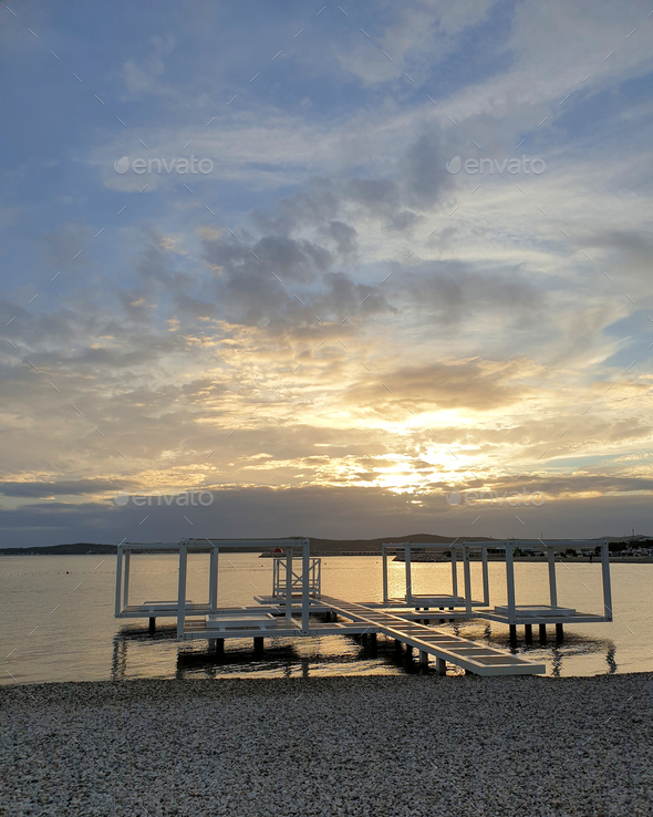 cabana over water on beach against sunset sky Stock Photo by Angela_Sikiric