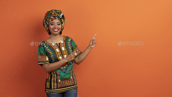 Pretty black woman in african costume pointing at free space Stock ...