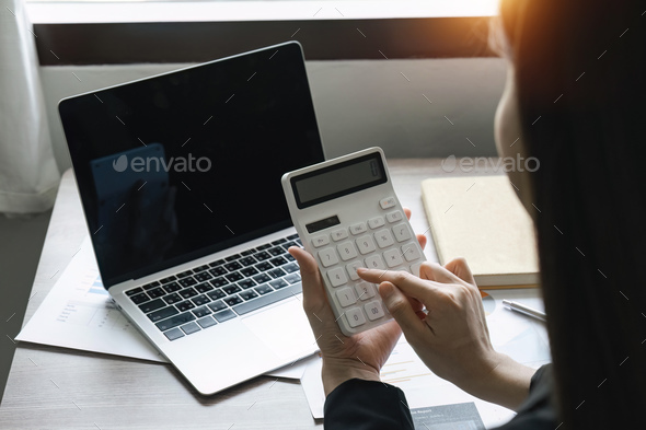 Bookkeeper using a calculator to calculate numbers on a company's ...