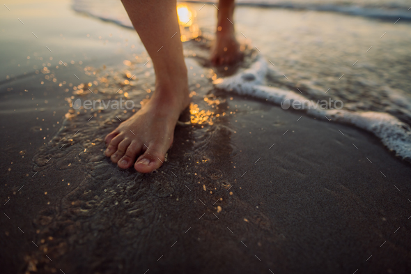 Woman walking on a beach during sunset, close-up of feet. Stock Photo ...