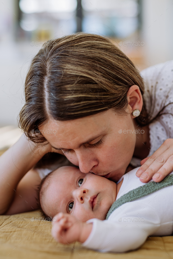 Portrait of mother kissing her newborn baby. Stock Photo by halfpoint