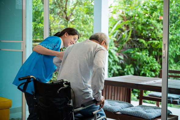 nurse is supporting elderly man sitting in wheelchair walking to looking out window Stock Photo ...